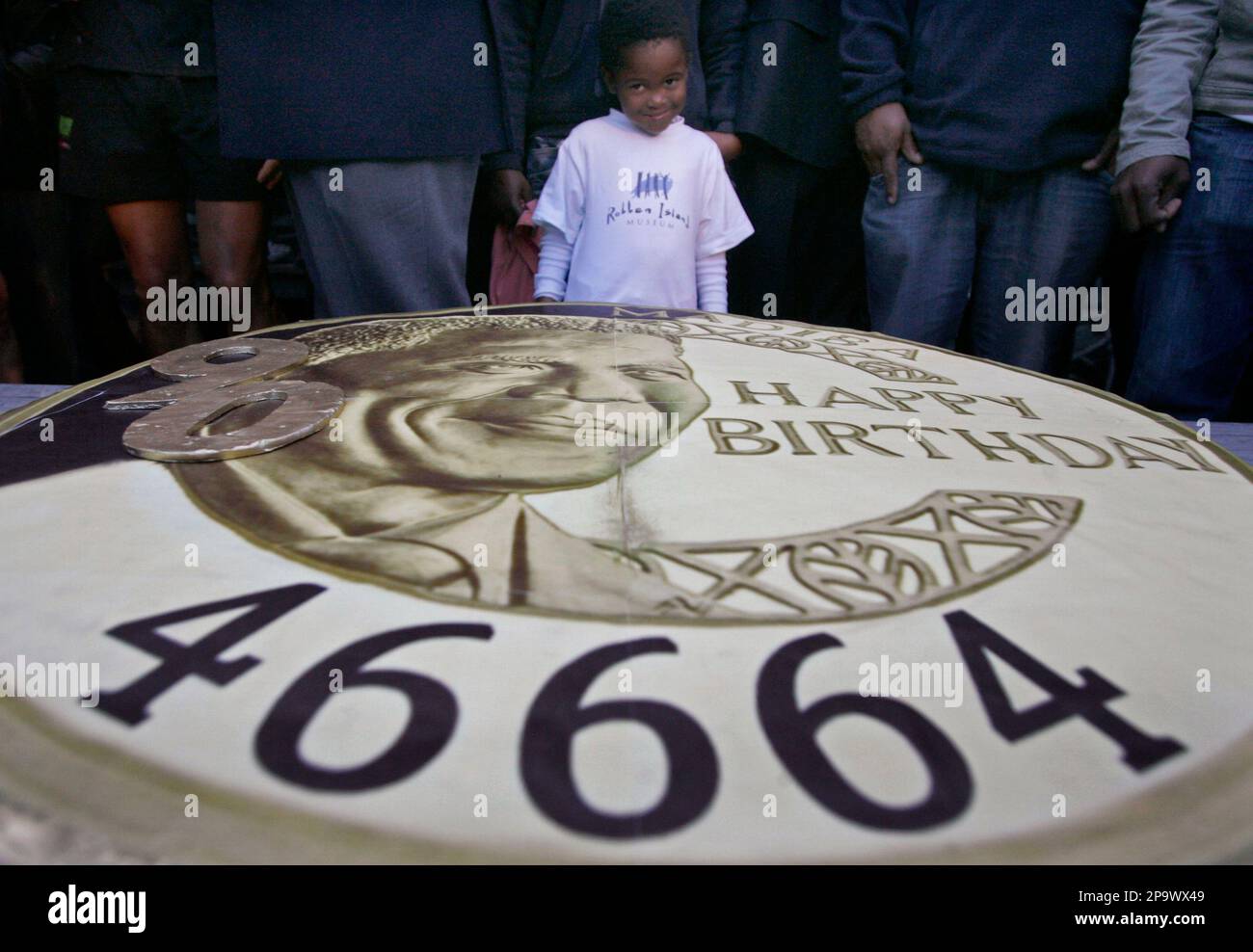A child stands in front of a cake made in honor of former South African ...