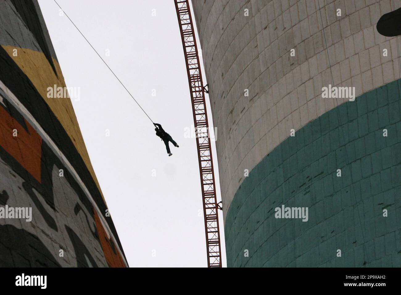 An abseiler swings between the old Orlando Power Station cooling towers ...