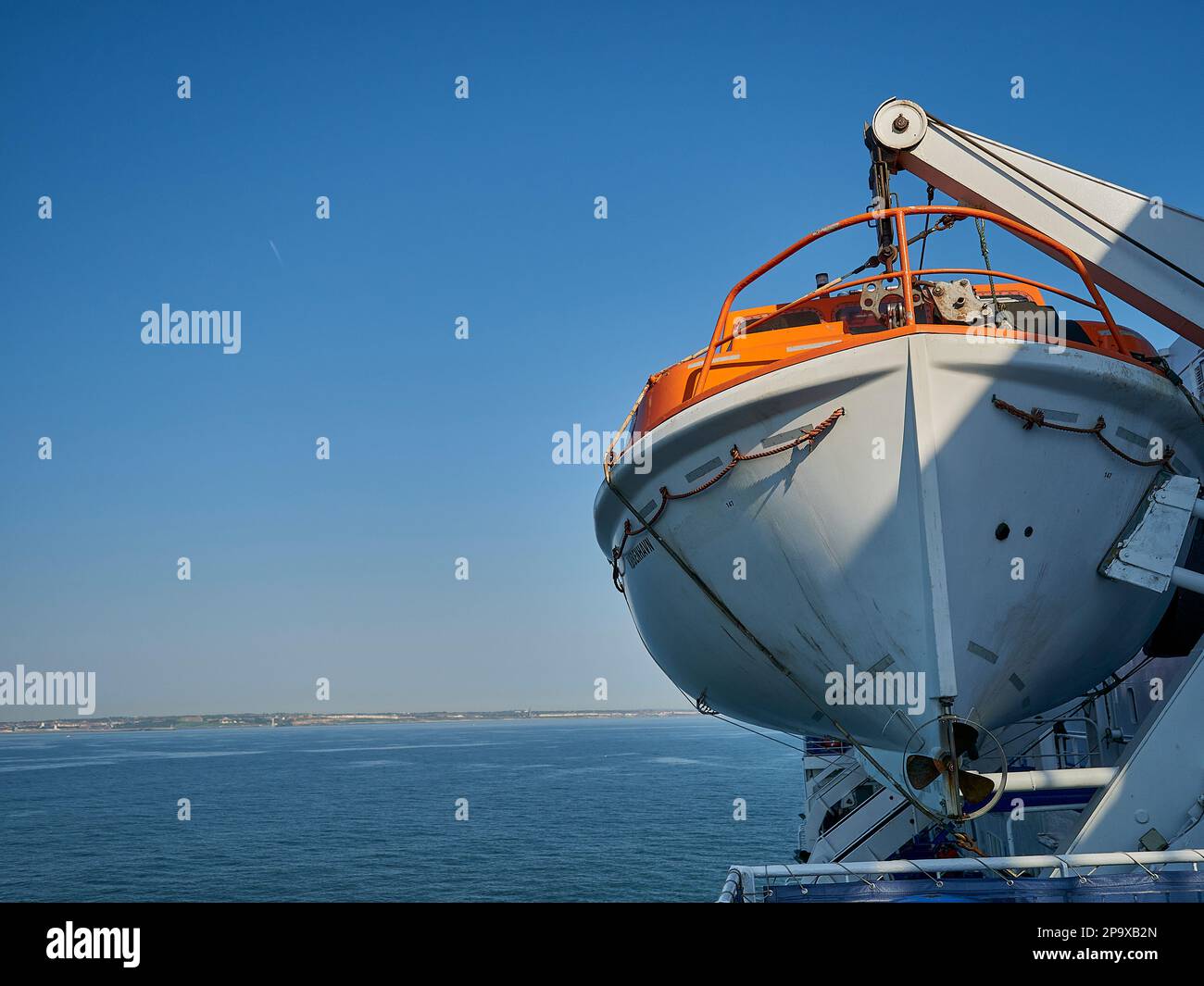 lifeboat hanging on the side of a boat driving over open sea on a clear ...