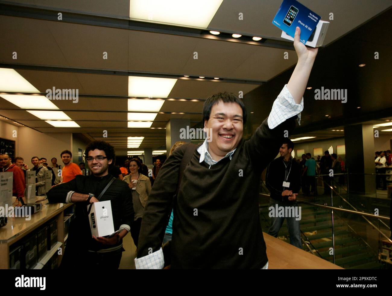 David Suen, right, the first customer, holds up his new Apple 3G iPhone ...