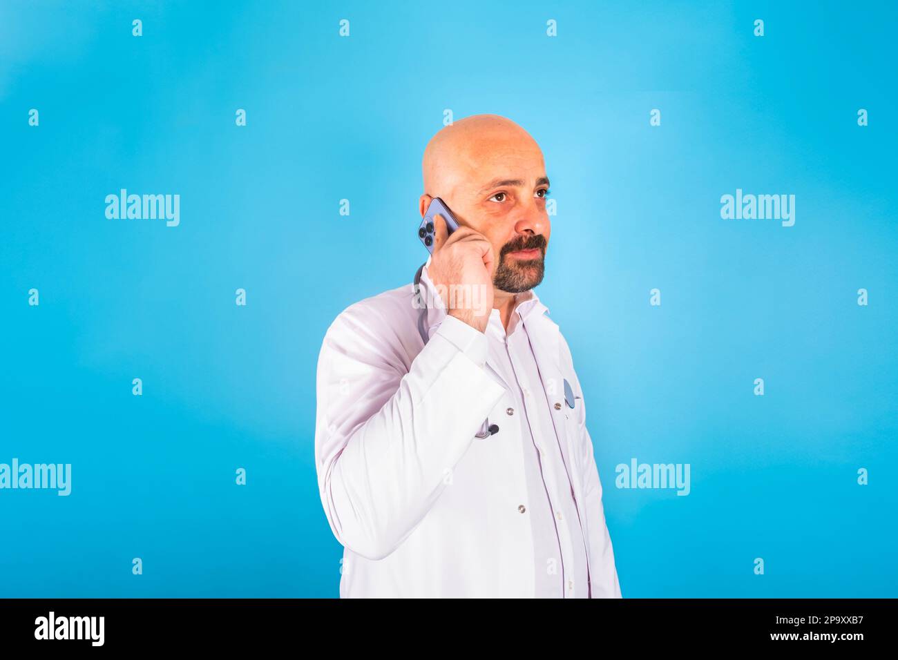 Caucasian male doctor talking on the phone. Standing over blue ...