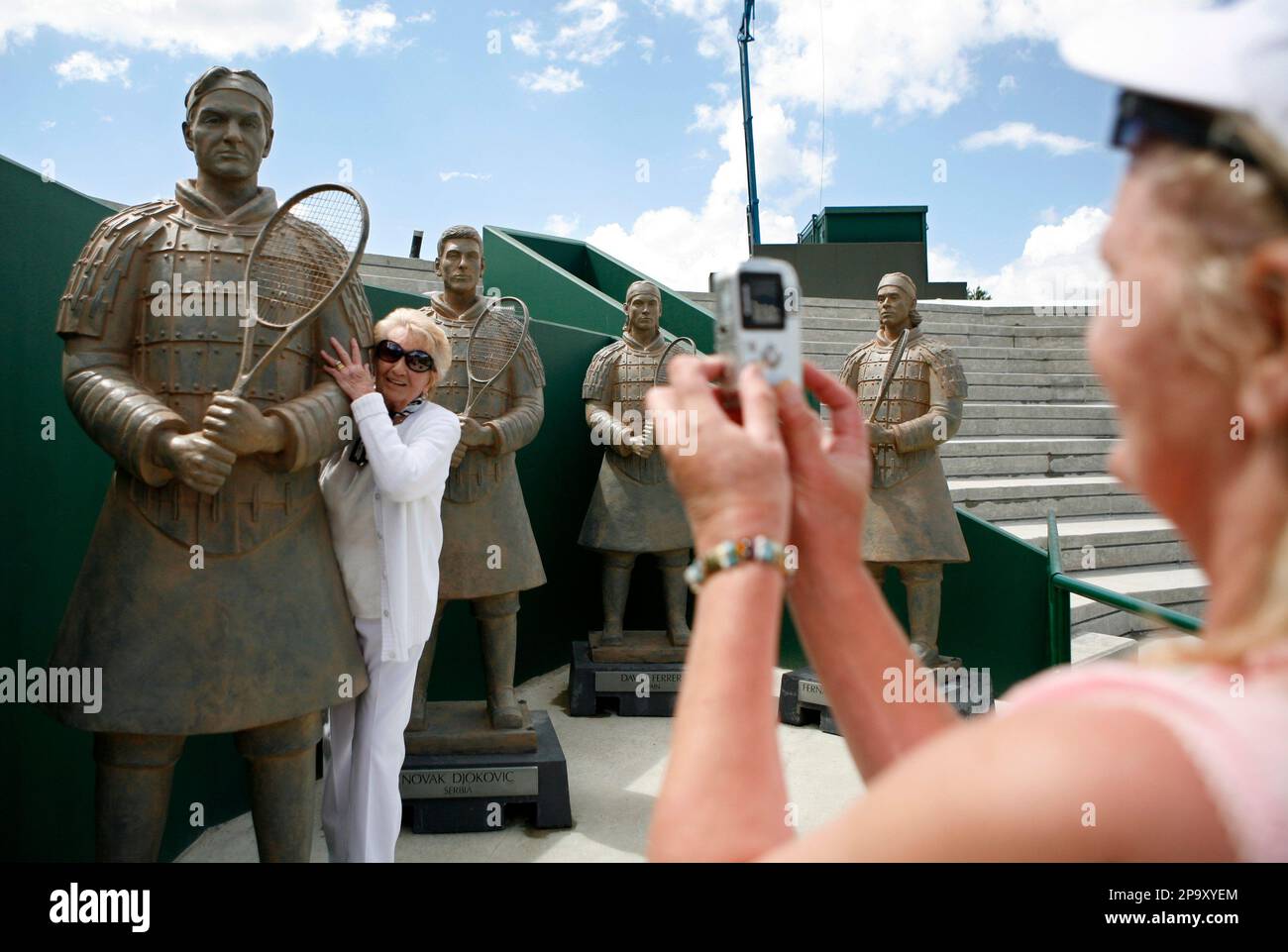 Visitors pose with a statue of the world number one tennis player Roger ...