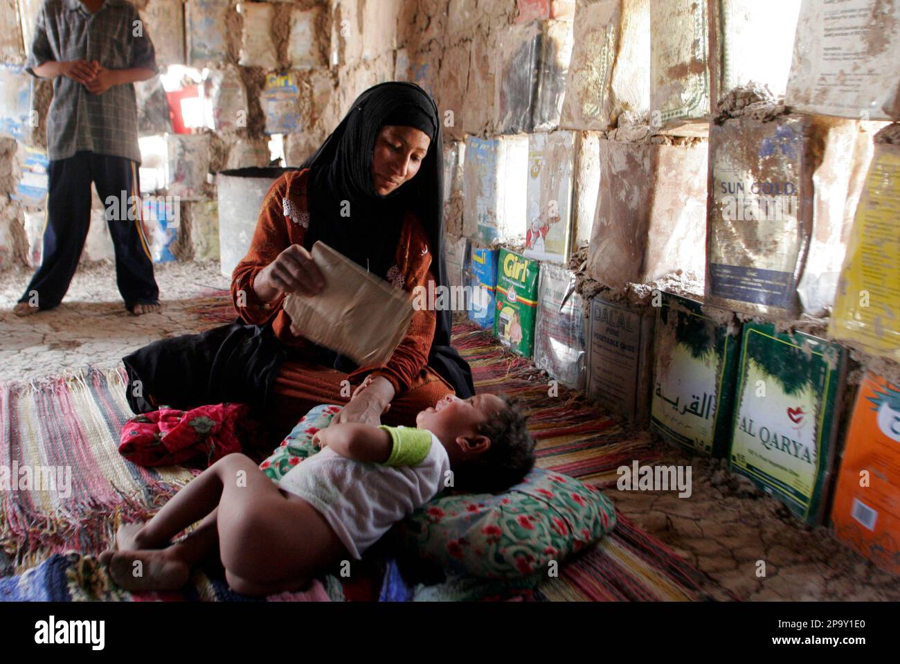 An internally displaced Iraqi cools down her child as she sits in a hut ...