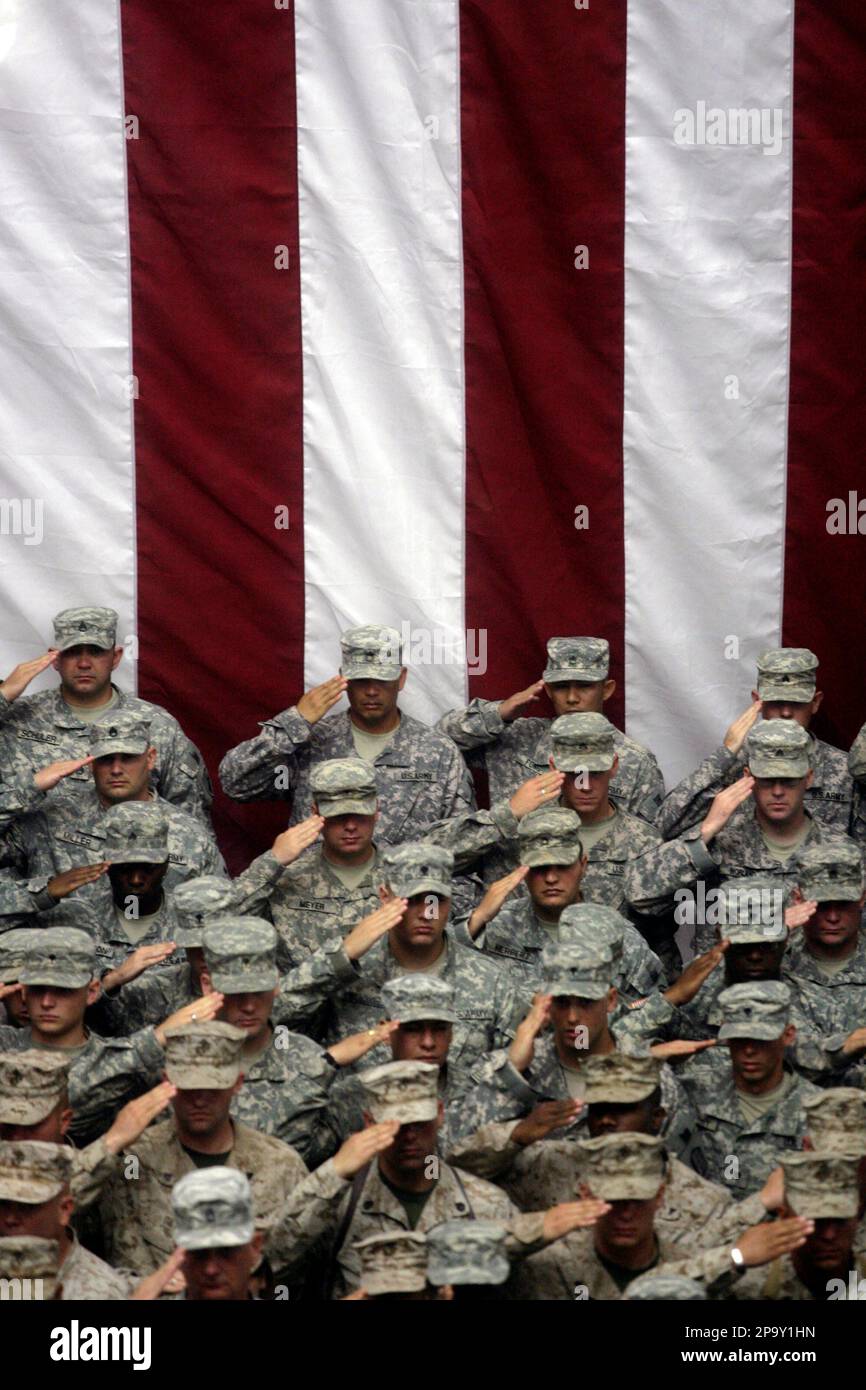 U.S. military service members salute at a mass re-enlistment ceremony ...