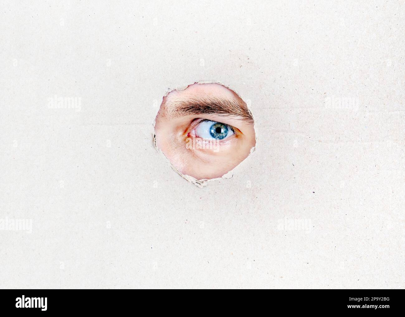 Eye peeking through a Hole in the Cardboard closeup Stock Photo - Alamy
