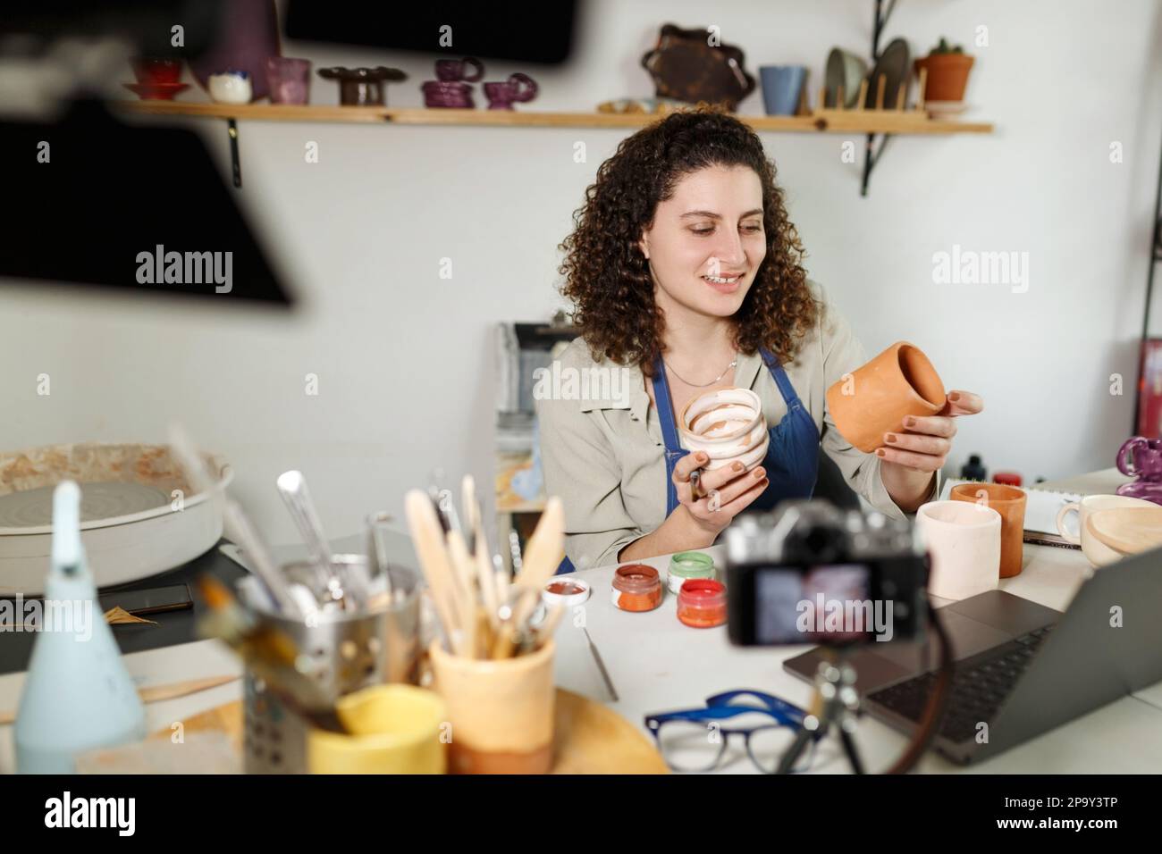 Females potter in blue apron making a vlog, recording online course ...