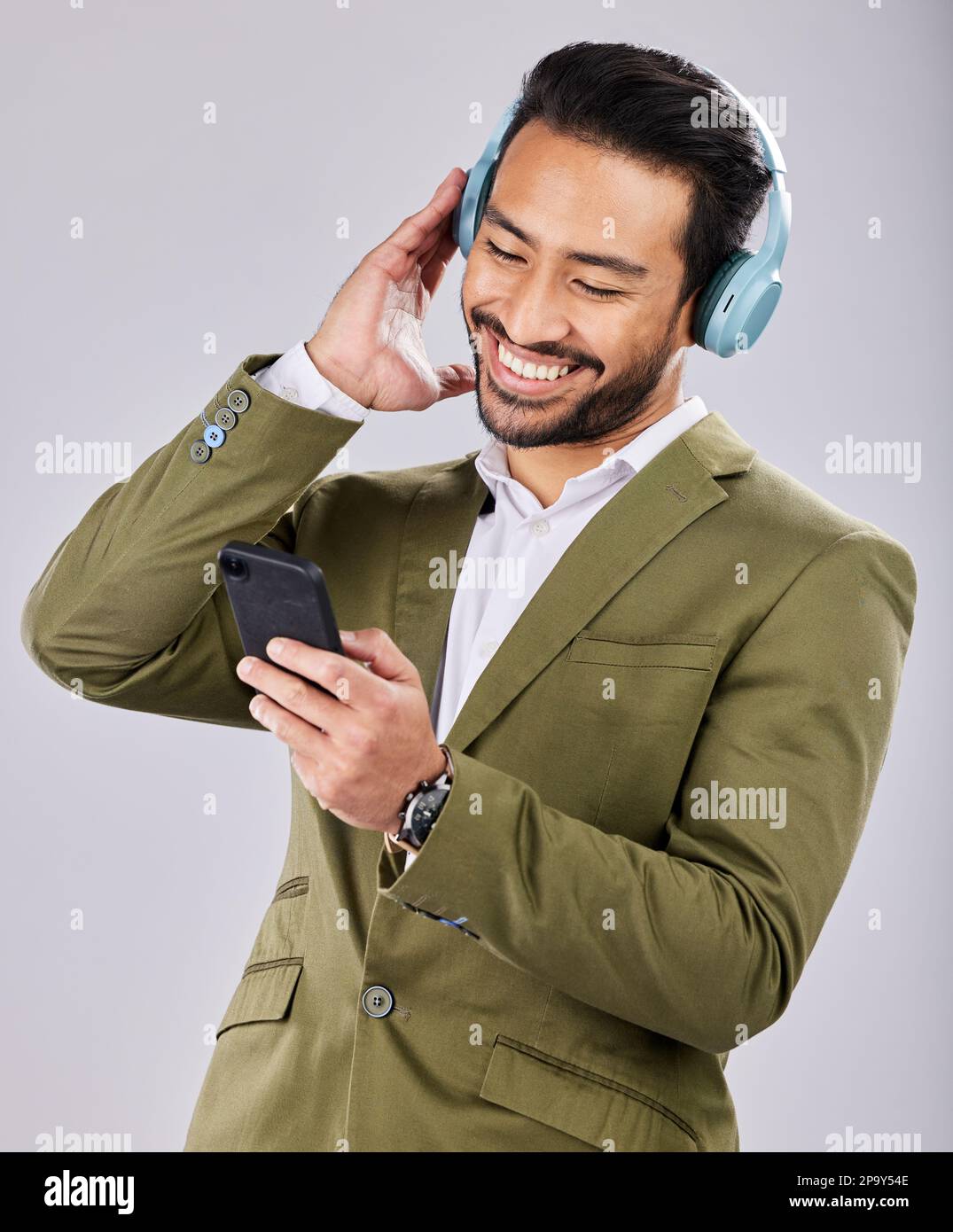 Asian man, phone and smile listening to music on headphones against a ...