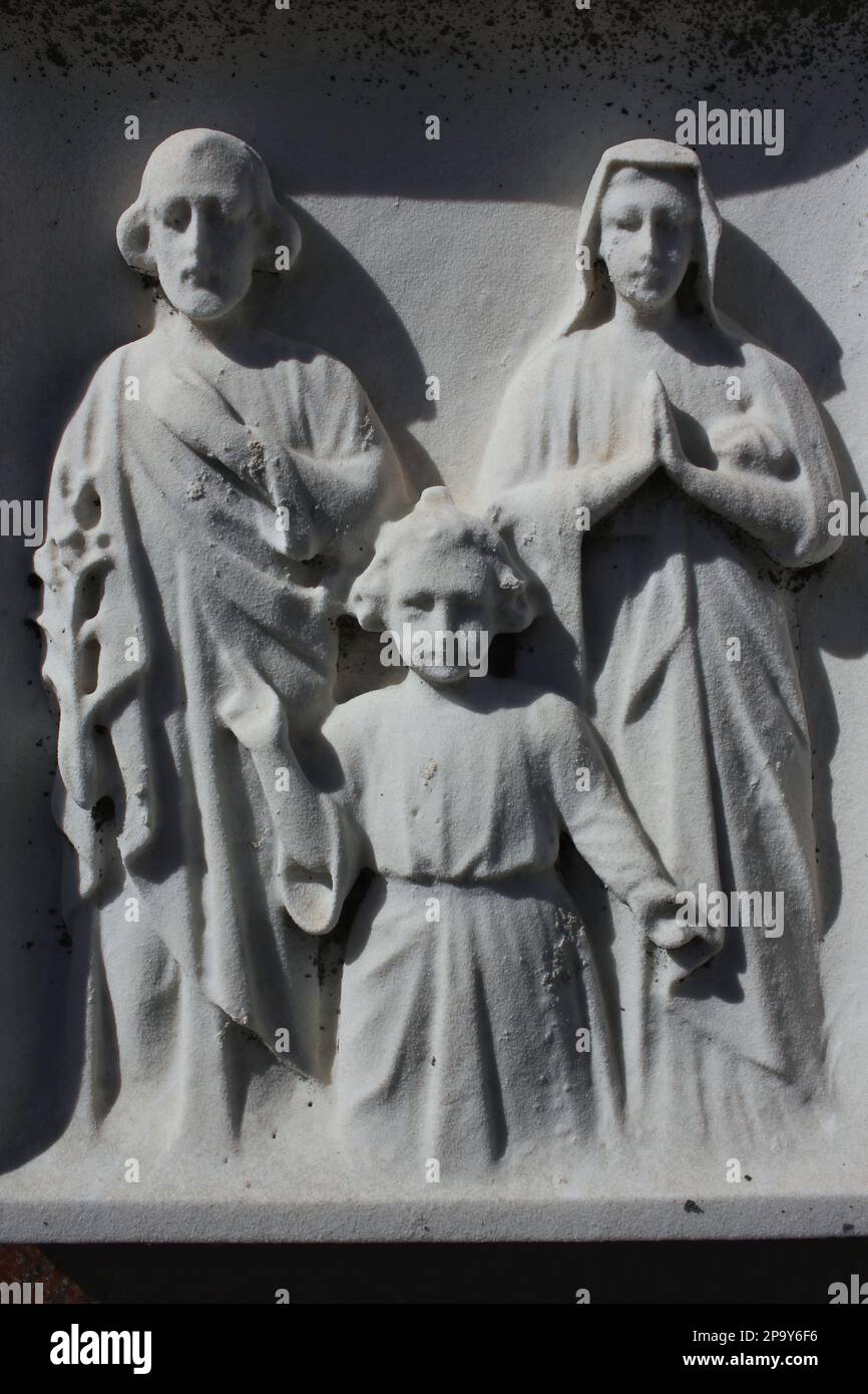 A carved stone statue of the Holy Family with a young Jesus standing ...