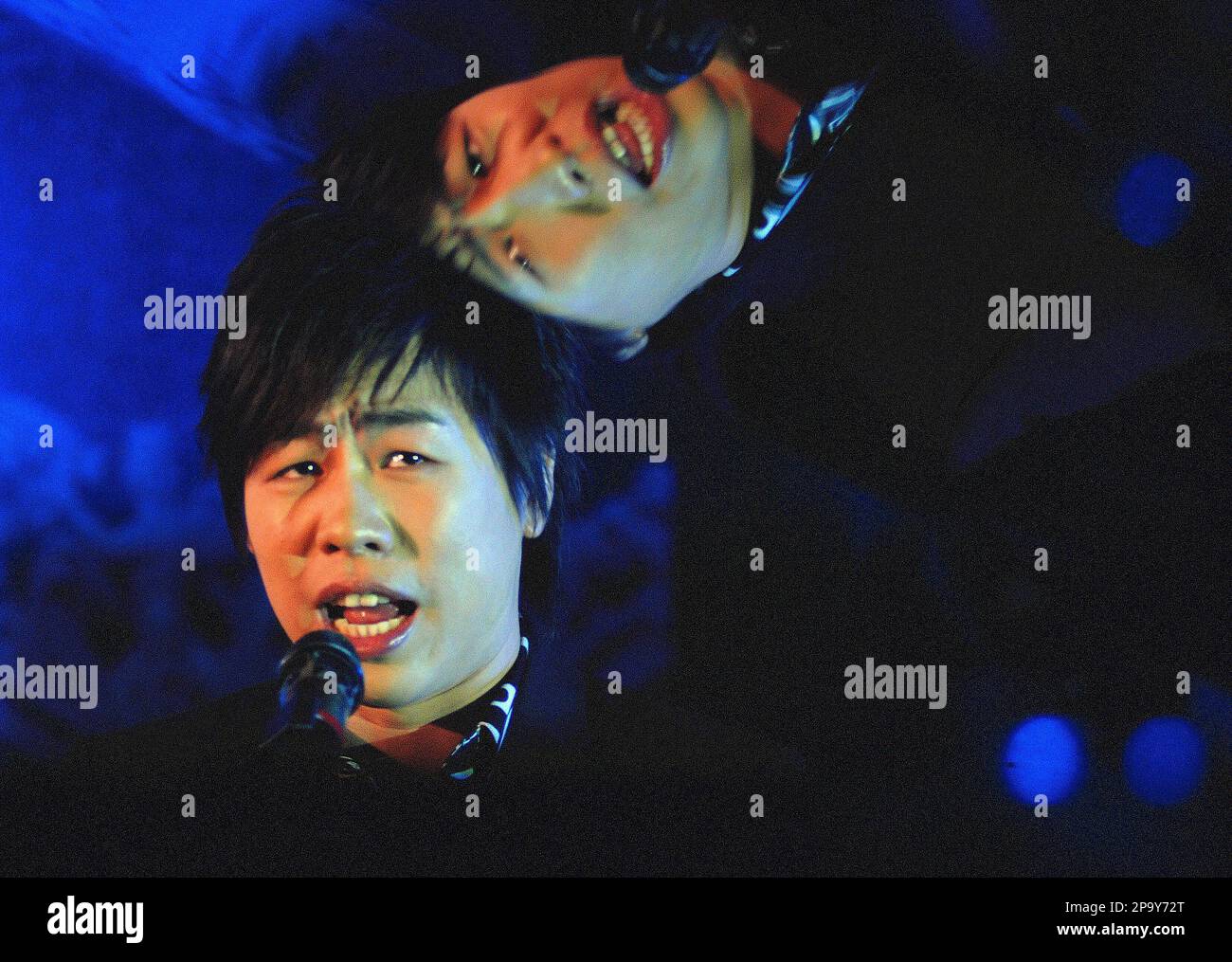 Chinese singer Anson Hu is reflected in a mirror as he sings during a ...