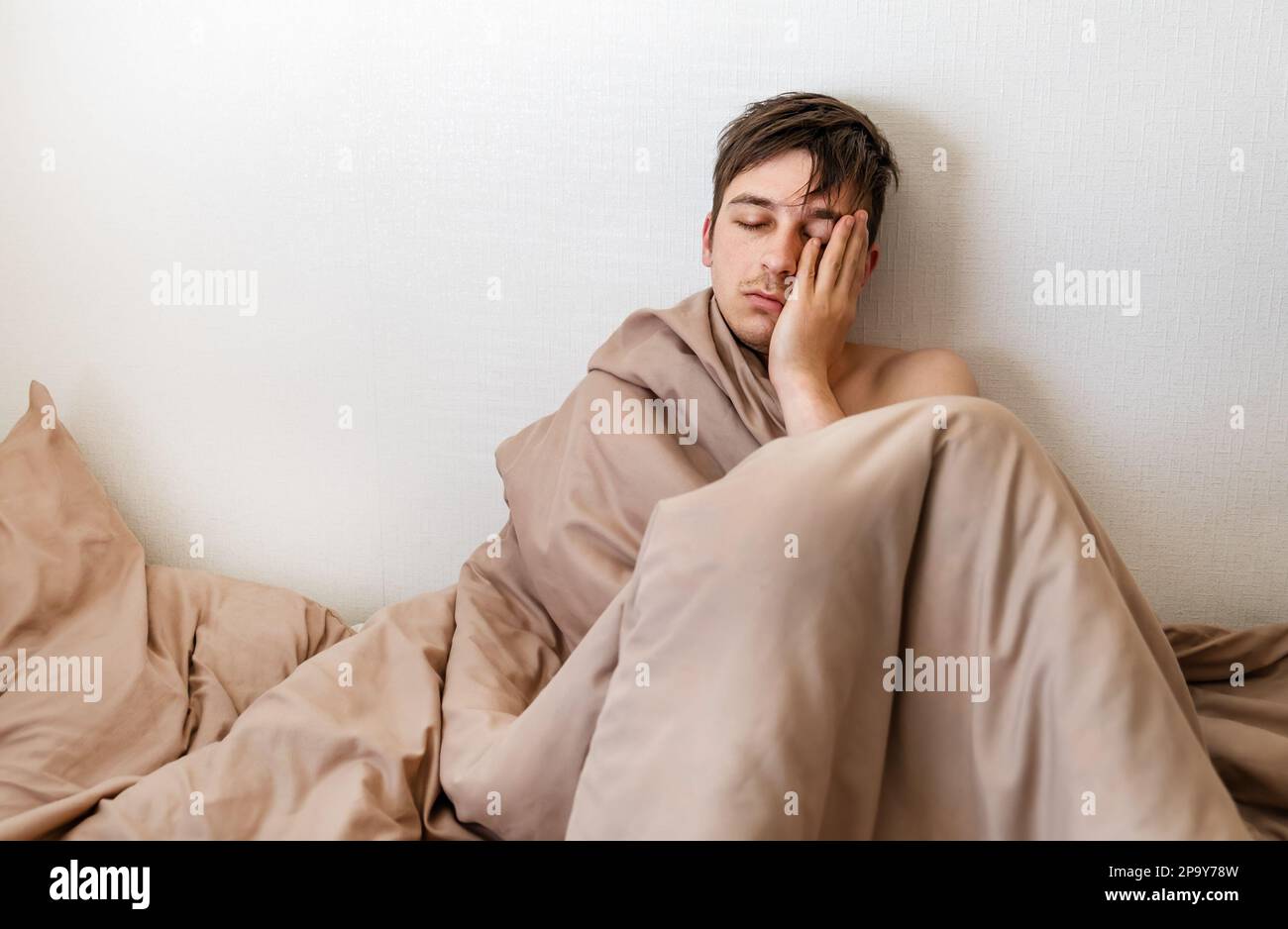 Sad Young Man in the Bed by the Wall Stock Photo - Alamy