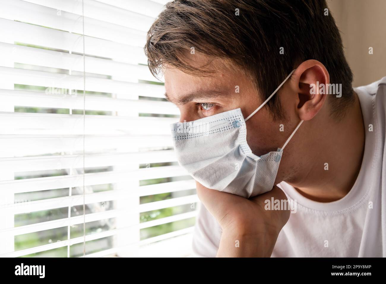 Sad Young Man in a Surgical Mask by the Window in the Room Stock Photo ...