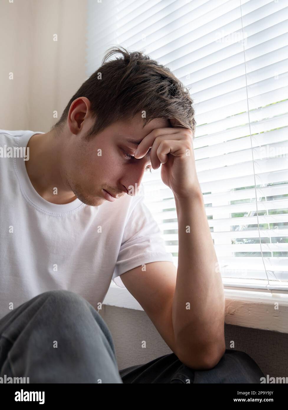 Sad Young Man by the Window in the Room Stock Photo - Alamy
