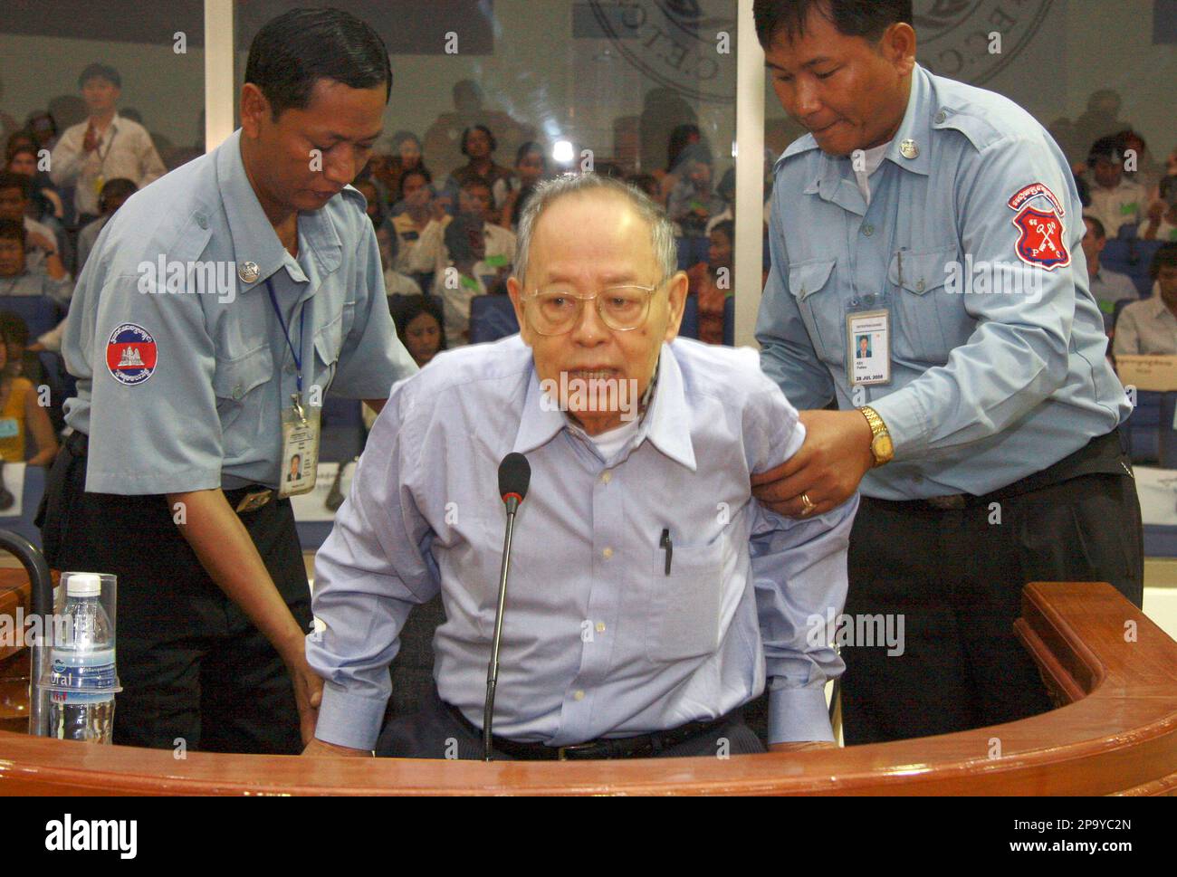 Former Khmer Rouge Foreign Minister Ieng Sary, center, is helped by security guards as he stands ...