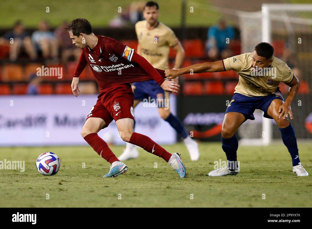 Craig Goodwin of Adelaide United is held back by Dane Ingham of the ...