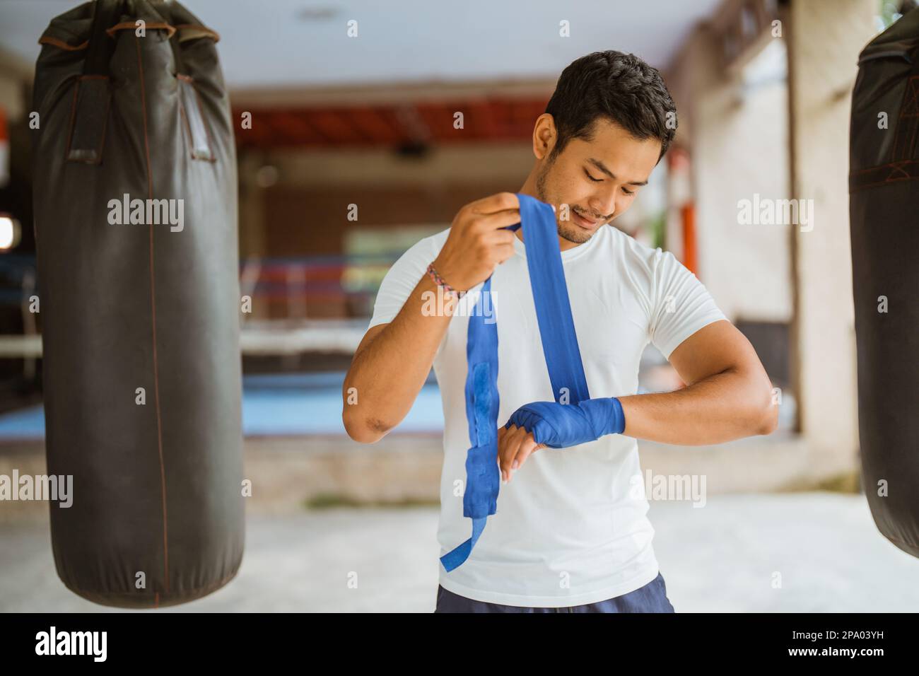 a asian male boxer wearing the boxing gloves while standing in ring ...