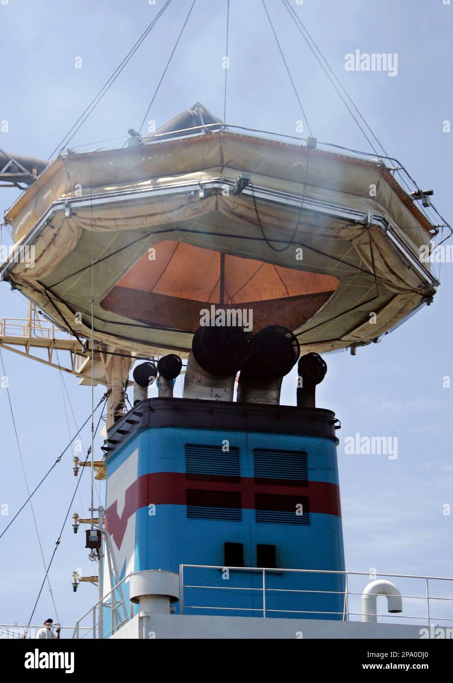 A crane lowers a large 'bonnet" over the funnel of a ship during a ...