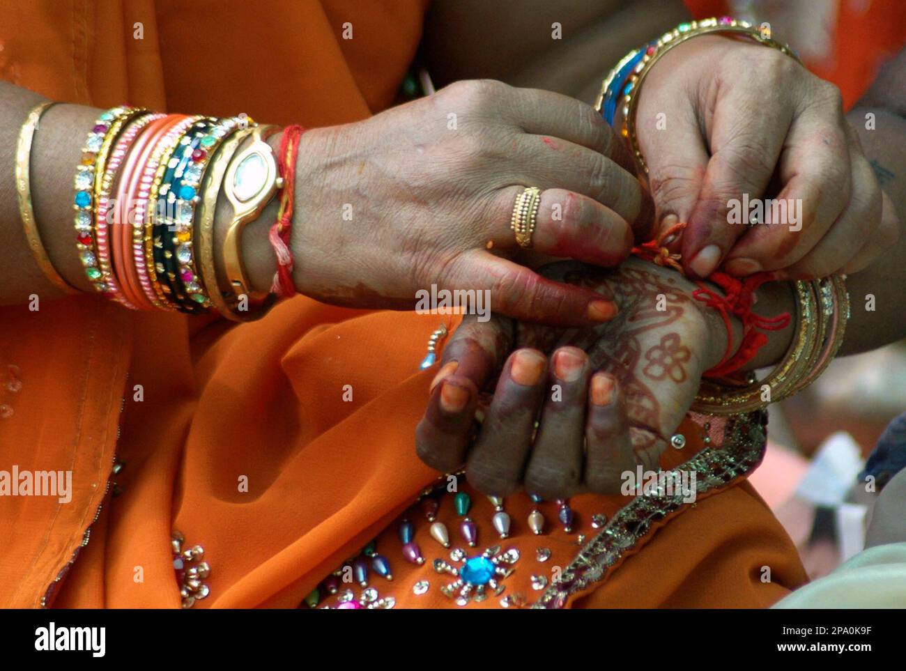 A married Hindu woman ties holy thread on another's wrist during Hindu ...