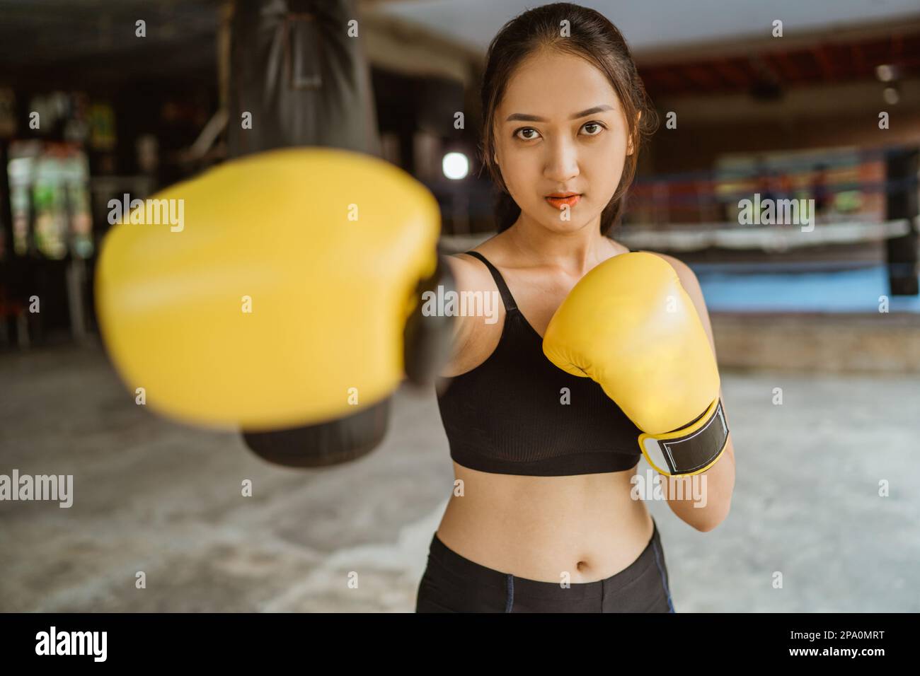 a female boxer with yellow boxing gloves standing with punching moves ...