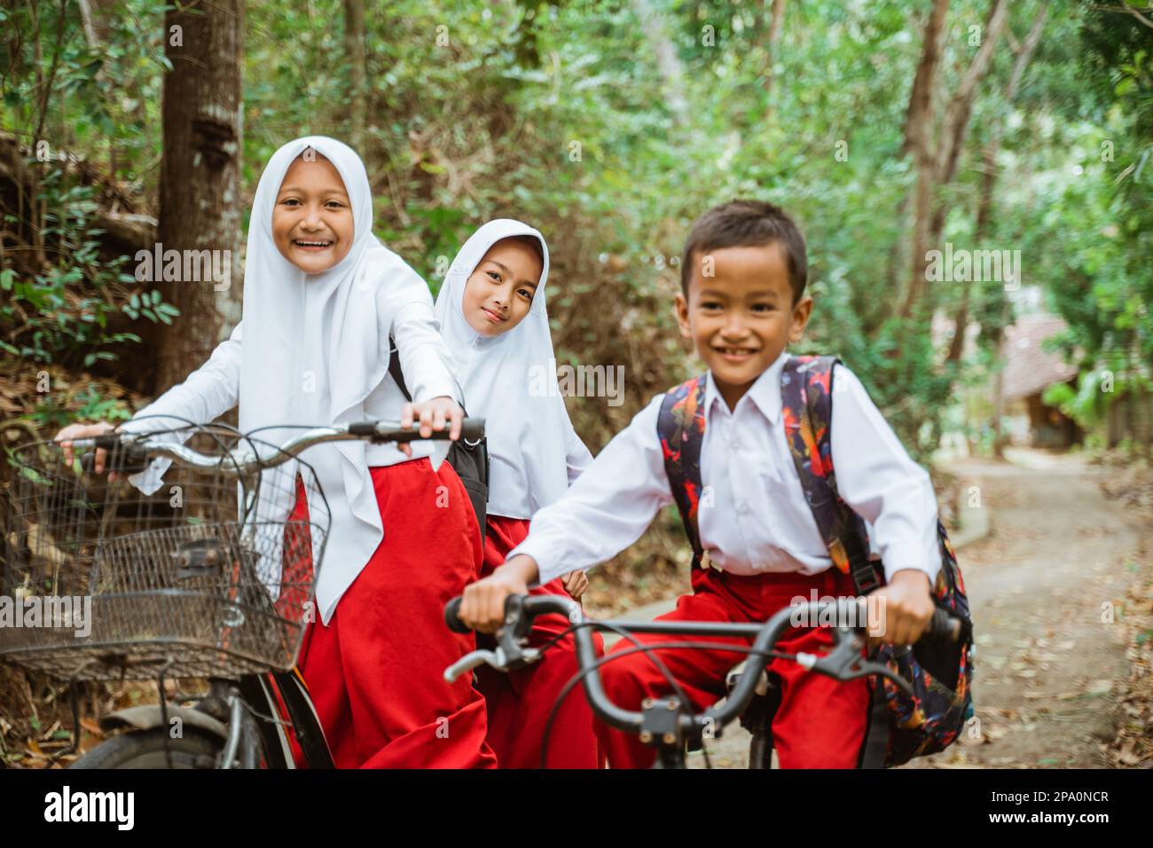 three elementary school students riding bike together to school Stock ...