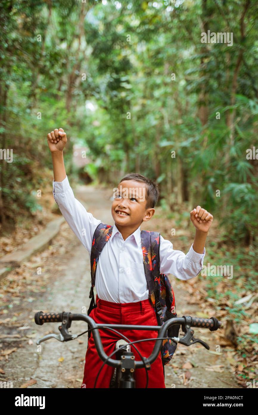 a male elementary student riding his bike and raised his hands Stock ...