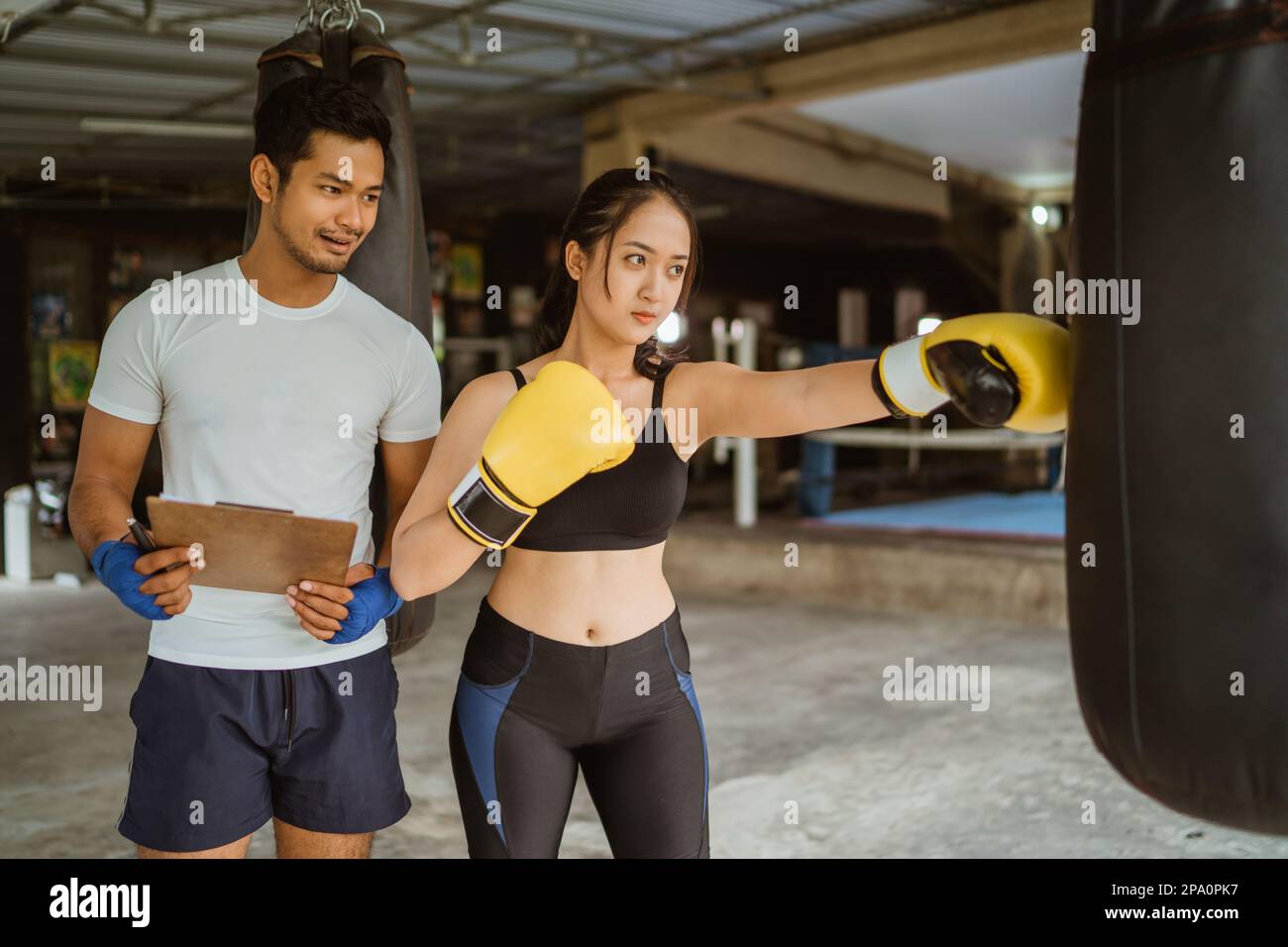 a boxing coach training the female boxer to punch the heavy bag Stock ...