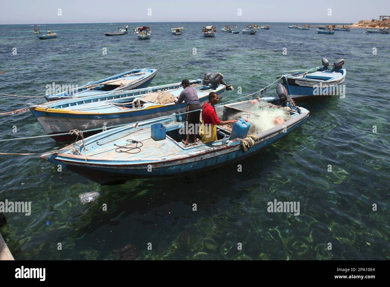 Two Libyan fishermen prepare a fishing boat in the harbor of the city ...
