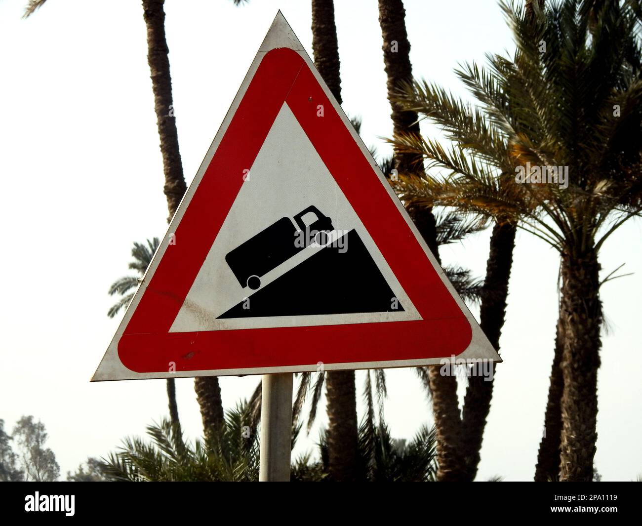 A traffic sign danger steep hill road ahead, a truck on an uphill ...