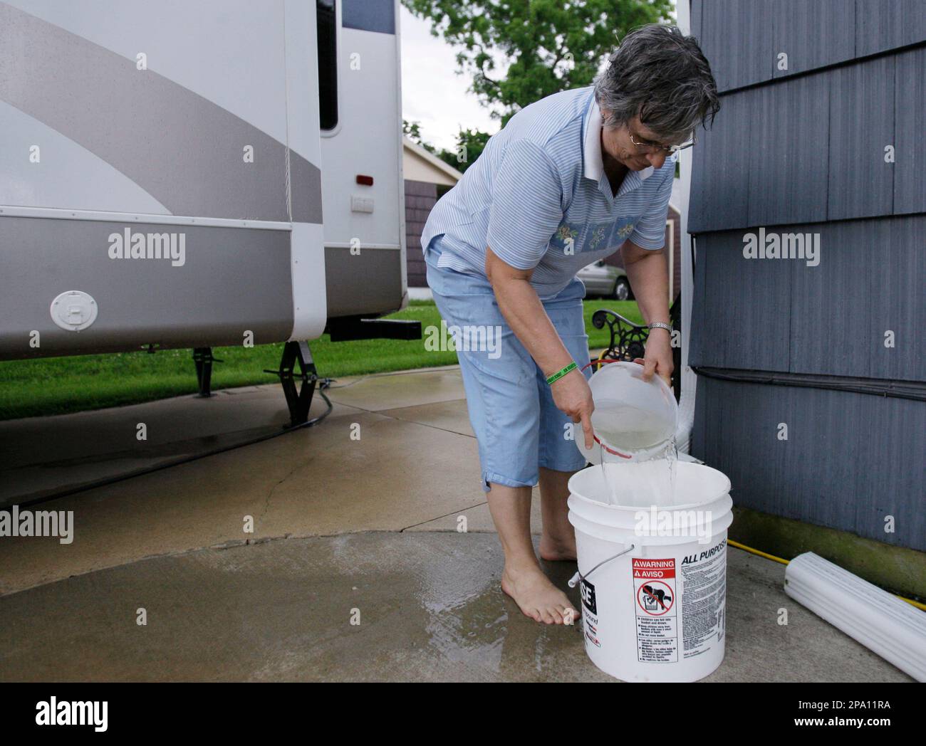 Marion Eberle transfers rain water from a collection bucket to a larger ...