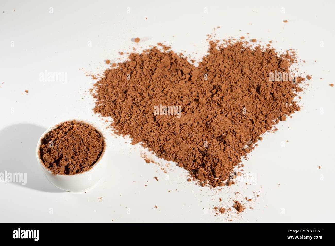 Poured heart-shaped cocoa powder, solated on white background Stock ...