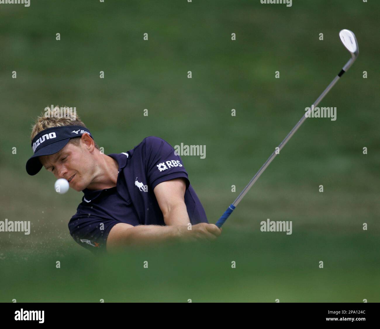 Luke Donald of England hits out of a bunker on the first green during ...