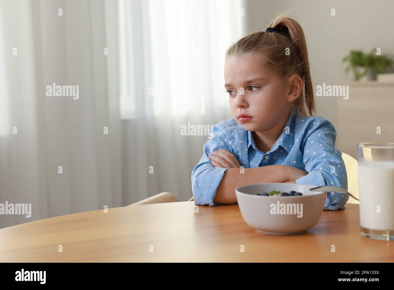 Cute little girl refusing to eat her breakfast at home, space for text ...