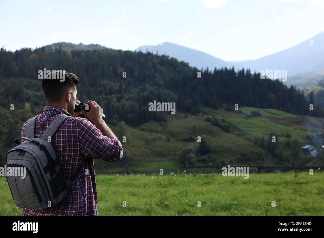 Tourist with backpack and binoculars enjoying landscape in mountains ...