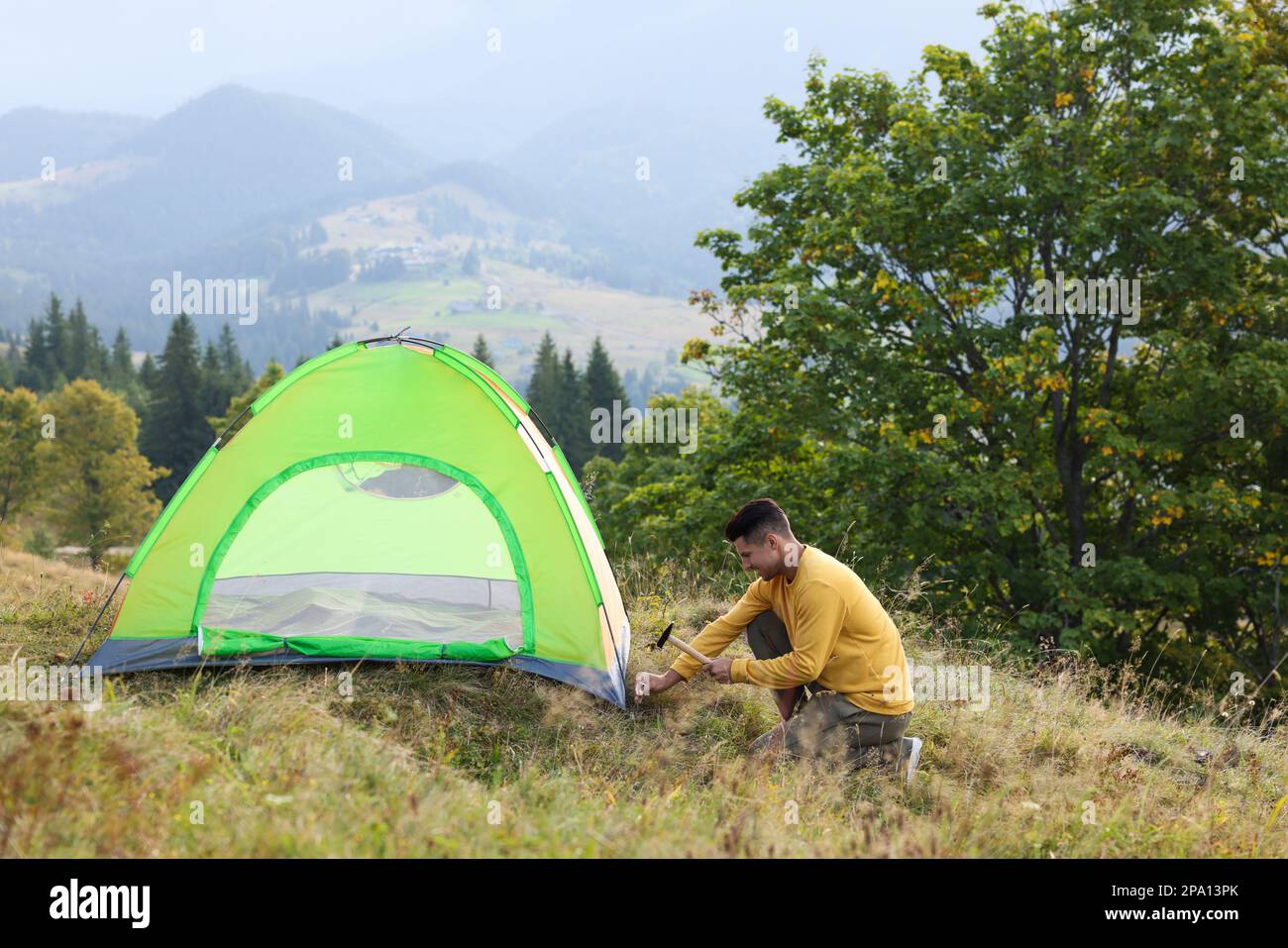 Man setting up camping tent in mountains Stock Photo - Alamy