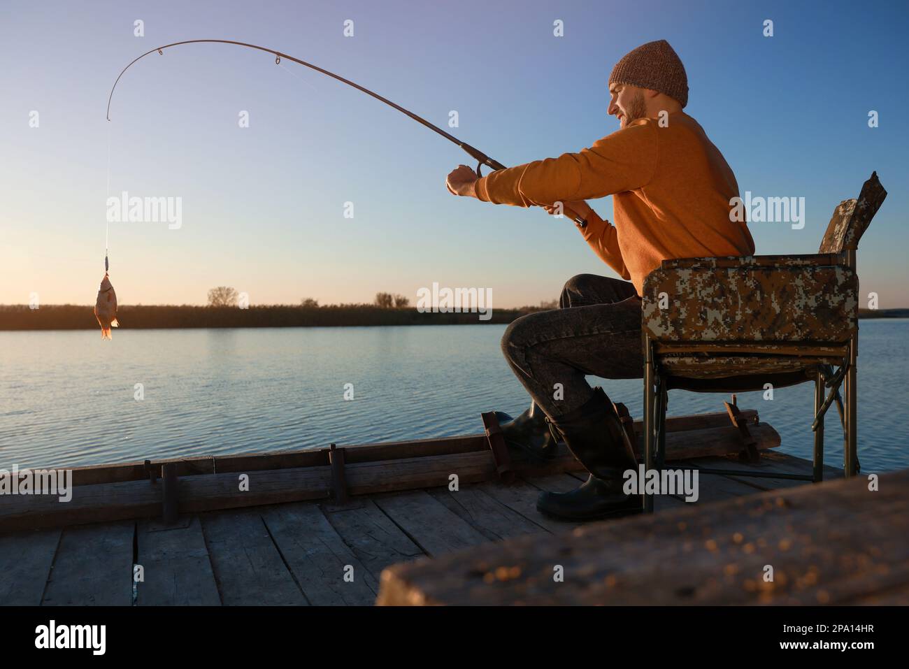 Fisherman catching fish with rod at riverside Stock Photo - Alamy