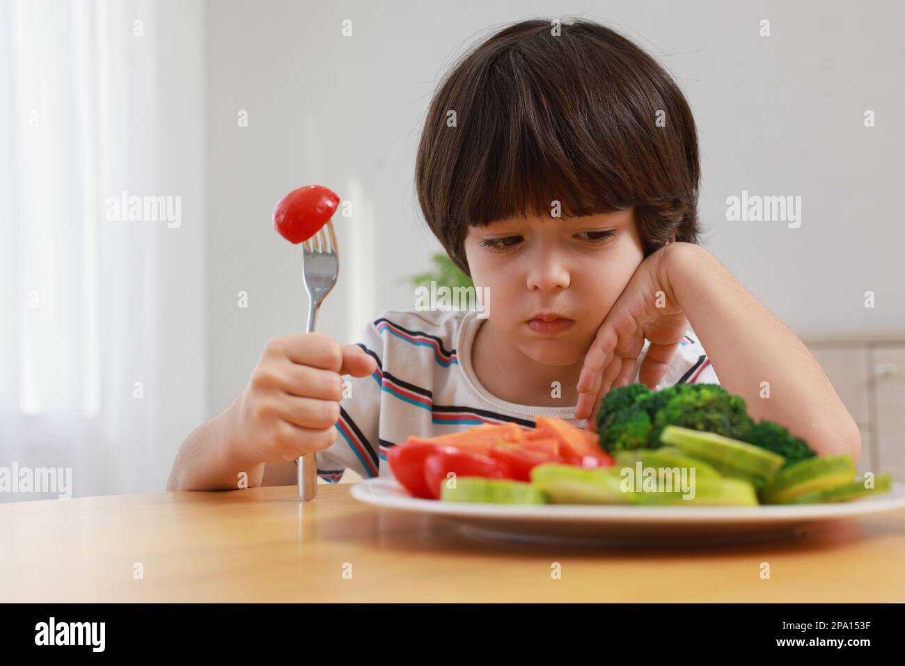 Cute little boy refusing to eat vegetables at home Stock Photo - Alamy