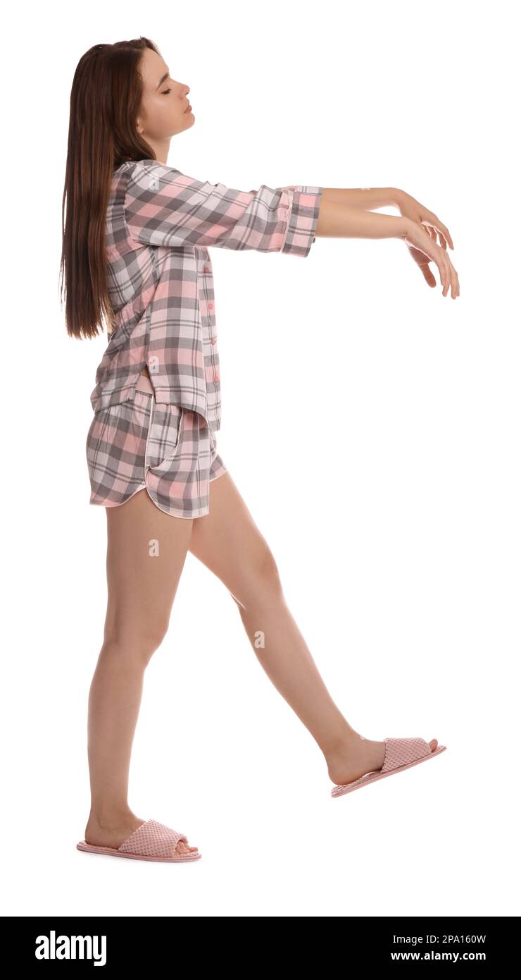 Young woman wearing pajamas and slippers in sleepwalking state on white ...