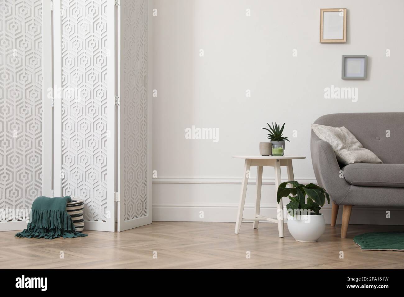 Stylish room with folding screen and sofa near white wall. Interior ...