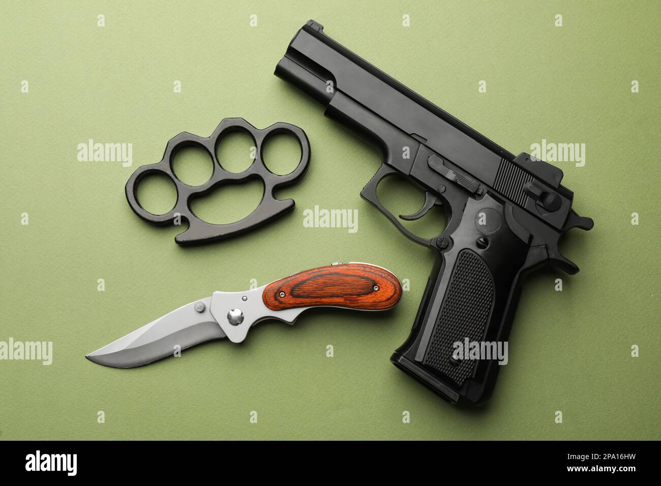 Black brass knuckles, gun and knife on green background, flat lay Stock ...