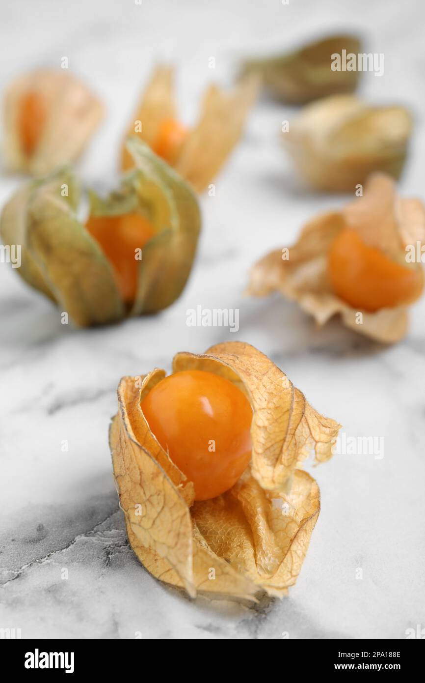 Ripe physalis fruits with dry husk on white marble table, closeup Stock ...
