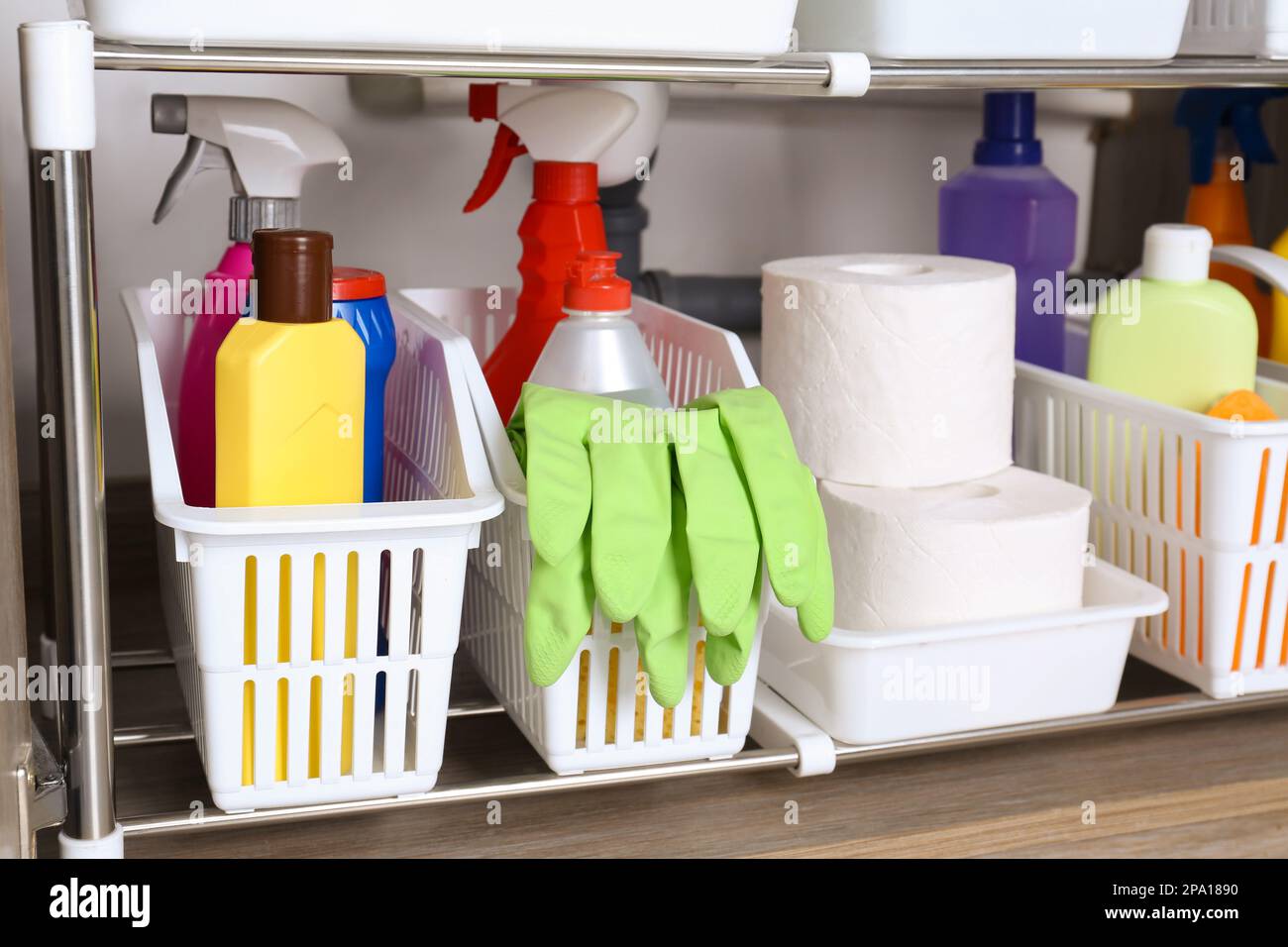 Open under sink cabinet with different cleaning supplies in kitchen ...