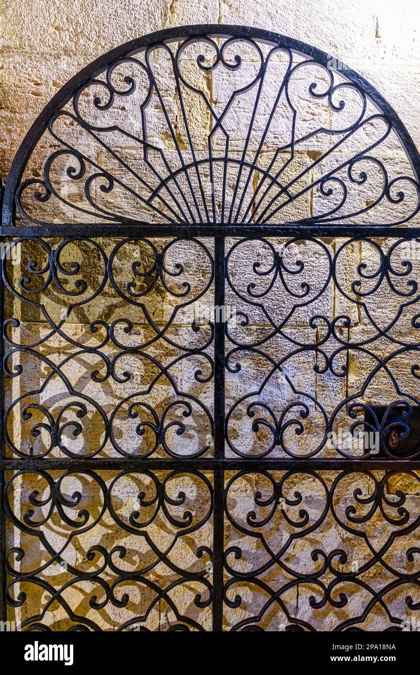 Arched metalwork grille in a chapel door. A stone-wall of the Catholic ...