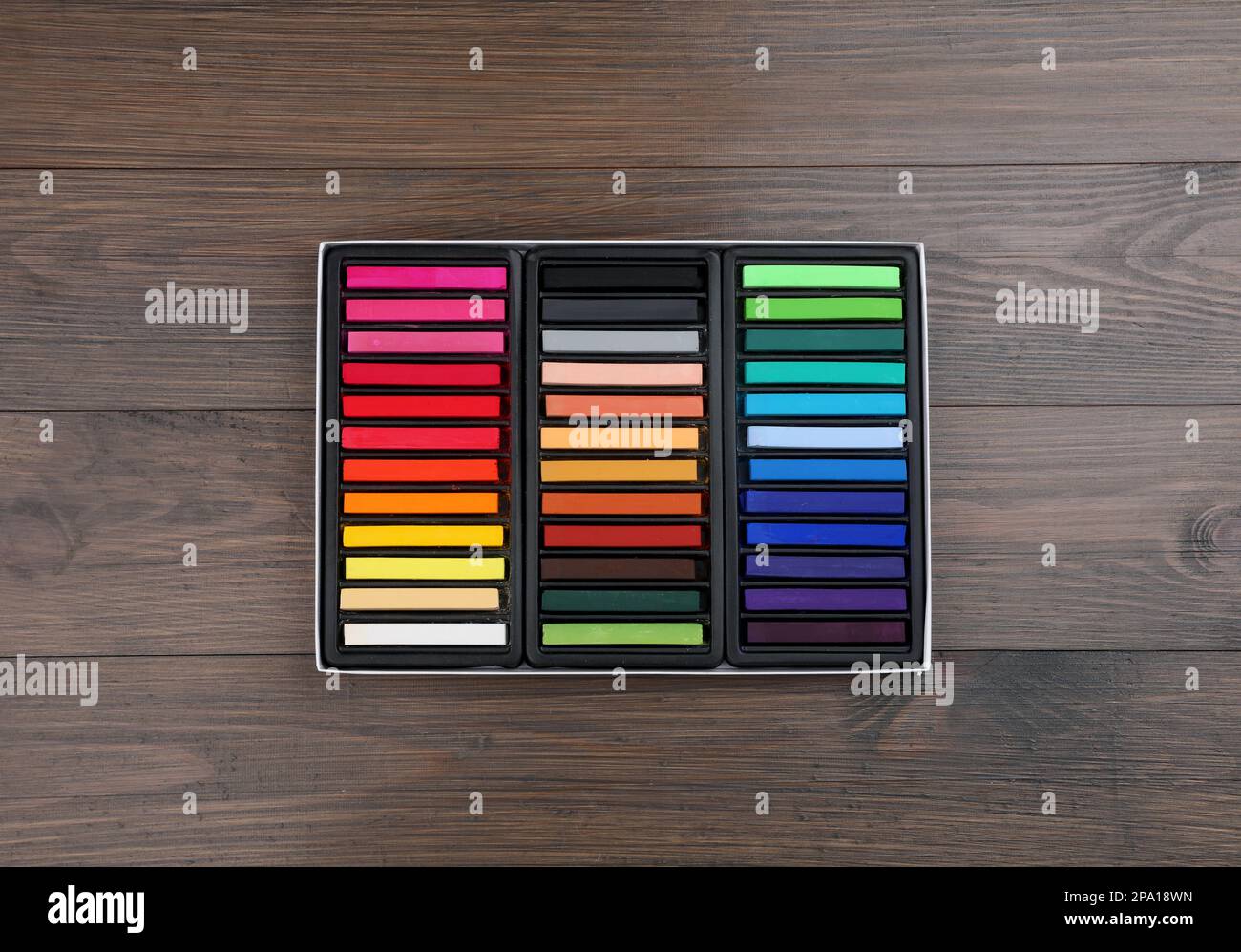 Set of colorful pastels in box on wooden table, top view. Drawing ...
