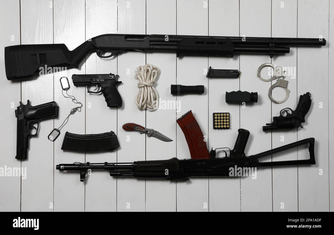 Flat lay composition with different guns on white wooden background ...