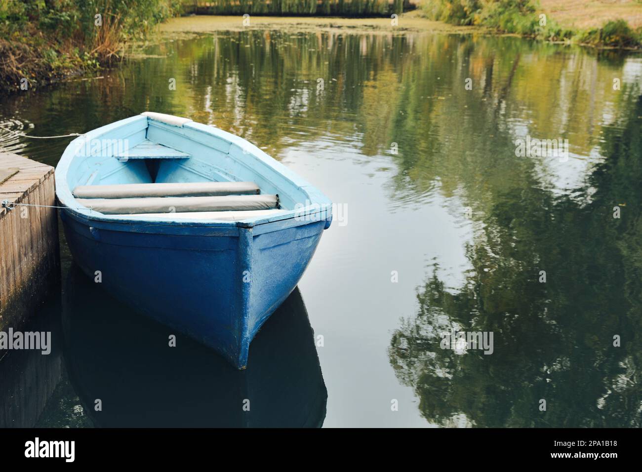 Light blue wooden boat on lake near pier, space for text Stock Photo ...