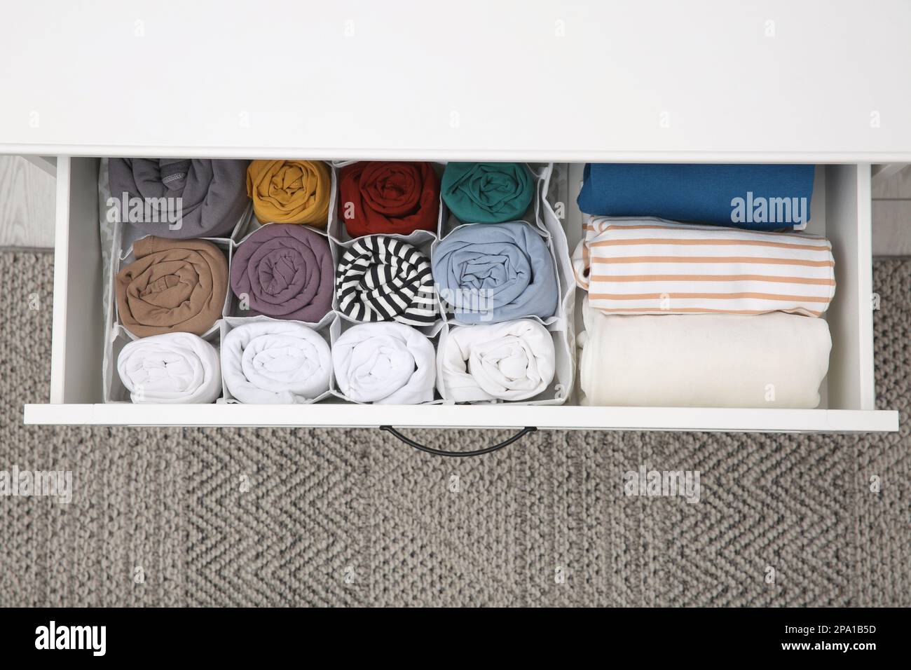 Open drawer with folded clothes indoors, top view. Vertical storage ...