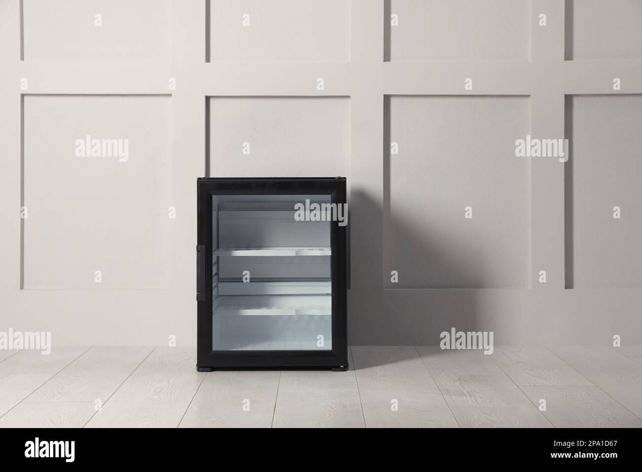 Empty mini bar with glass door near beige wall indoors. Space for text ...