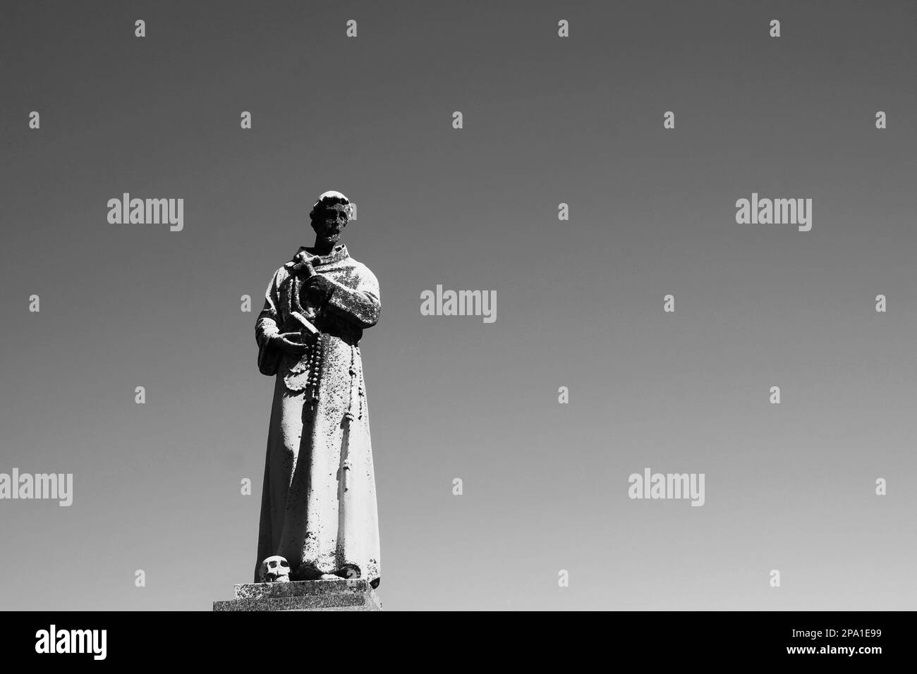 A natural stone statue of St Joseph holding a book and across while ...