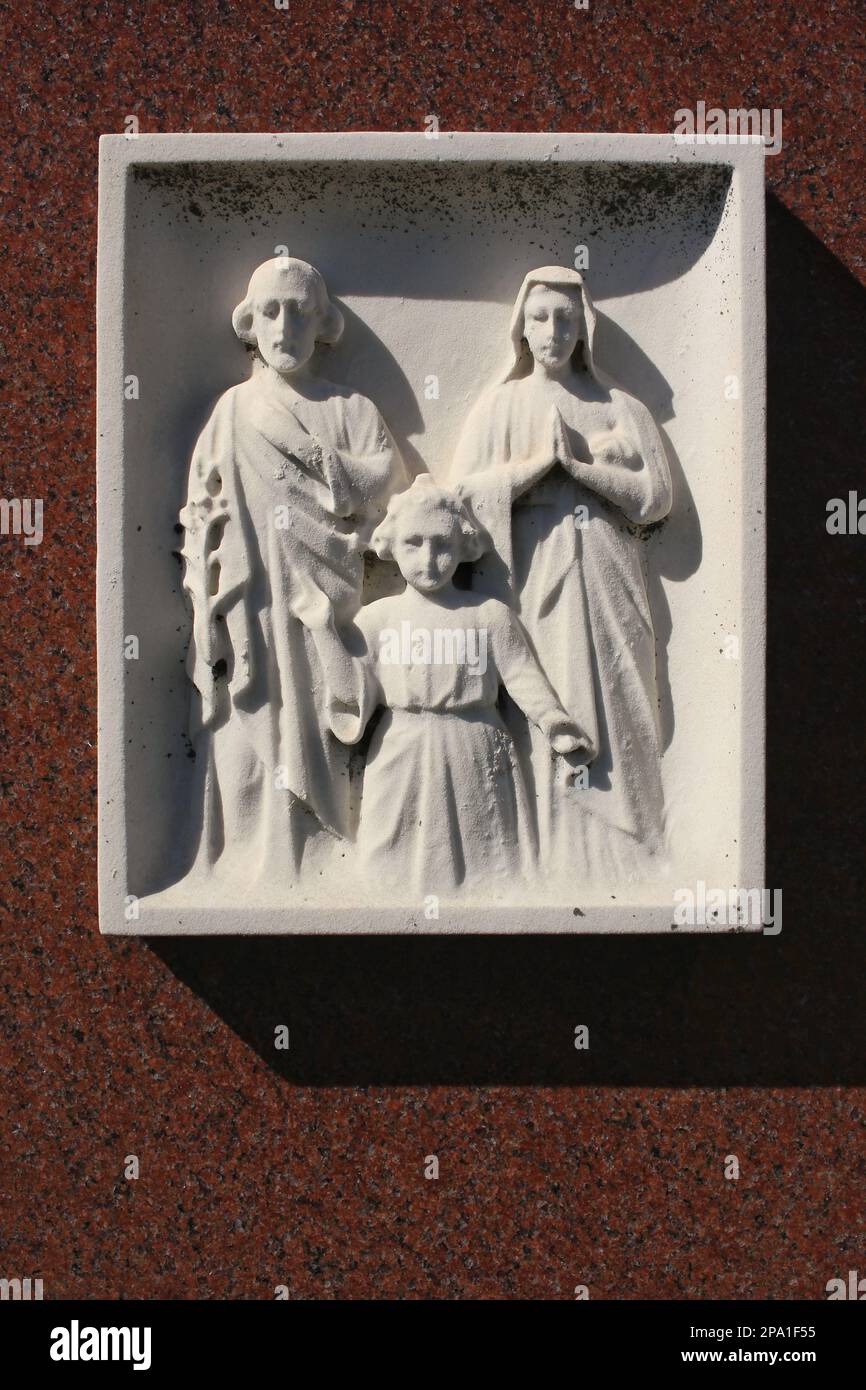 A carved stone statue of the Holy Family with a young Jesus standing ...