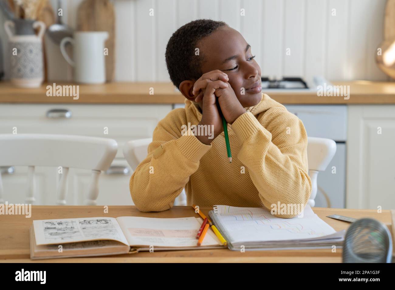 Smiling dreamy child African American boy procrastinating on doing ...