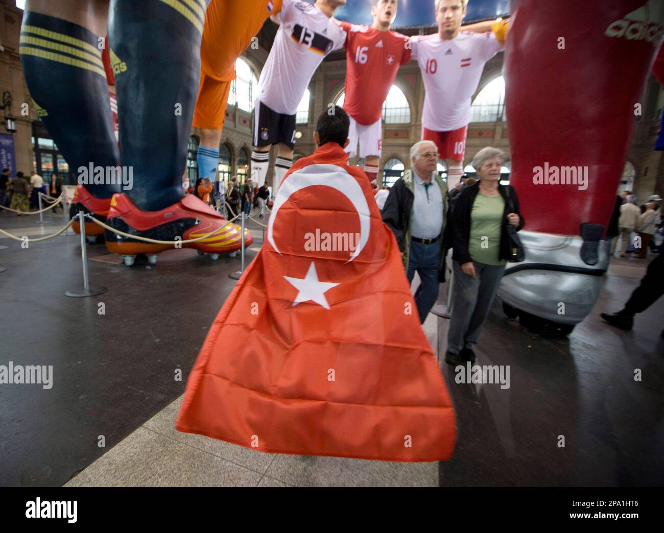 A soccer fan wrapped in a Turkish flag walks towards giant mannequins ...